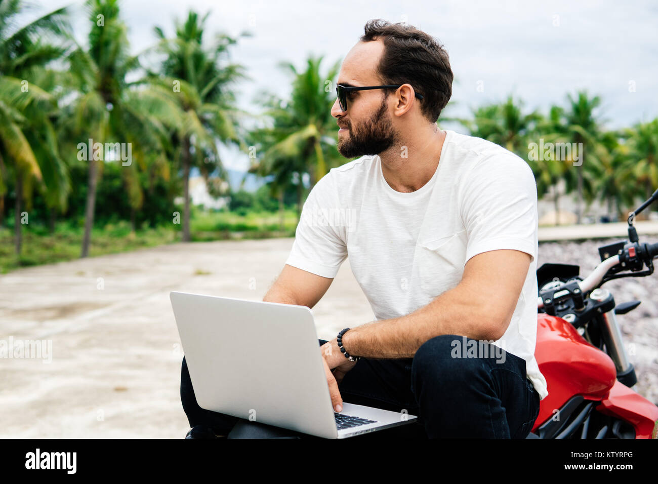 Man working on laptop while sitting on his motorcycle Stock Photo - Alamy