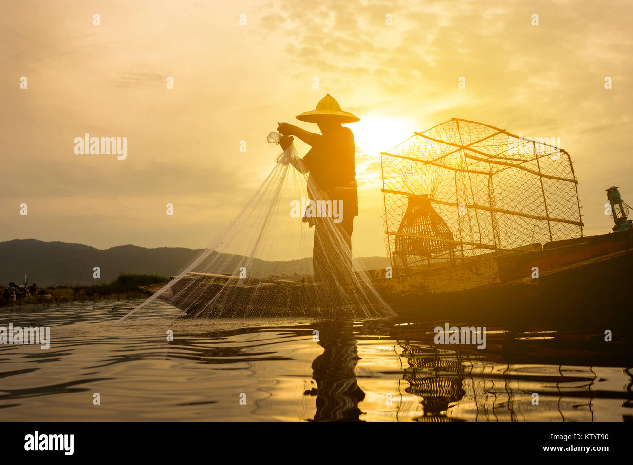fisherman on wooden boat casting a net for catch a fish in nature river ...