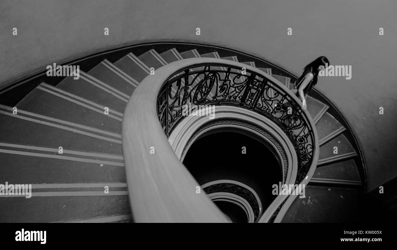 Woman going down spiral stairs hi-res stock photography and images - Alamy