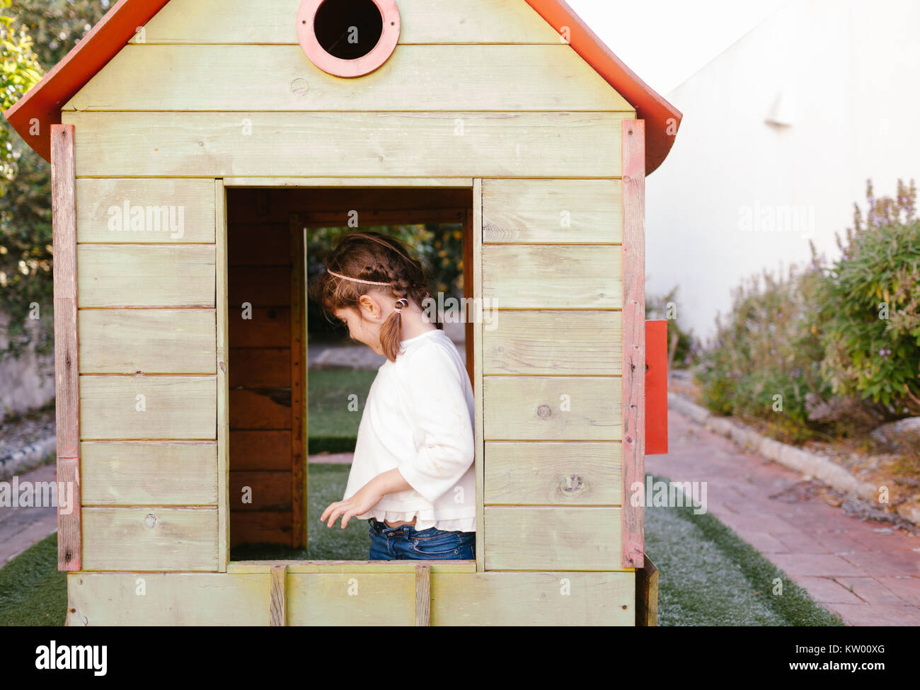 girl leaning out of the window of a green wooden cabin in the garden of ...