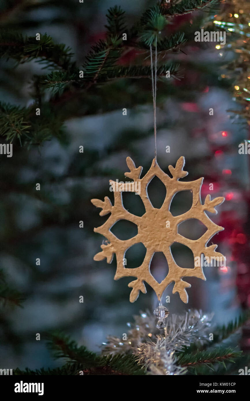 A snow flake made of fabric hanging on a traditional Christmas tree in ...