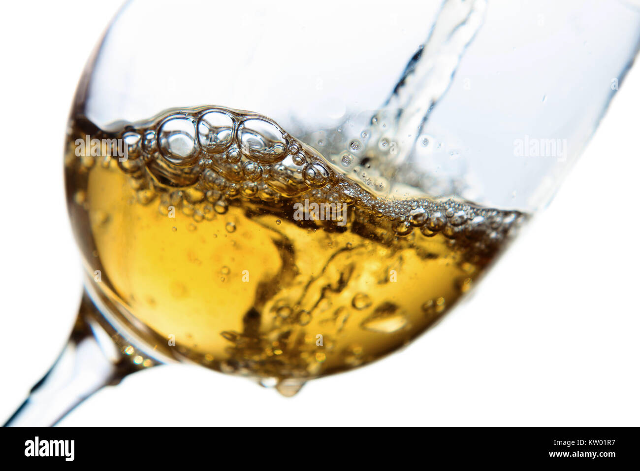 White wine being poured into a wineglass, isolated on white background ...
