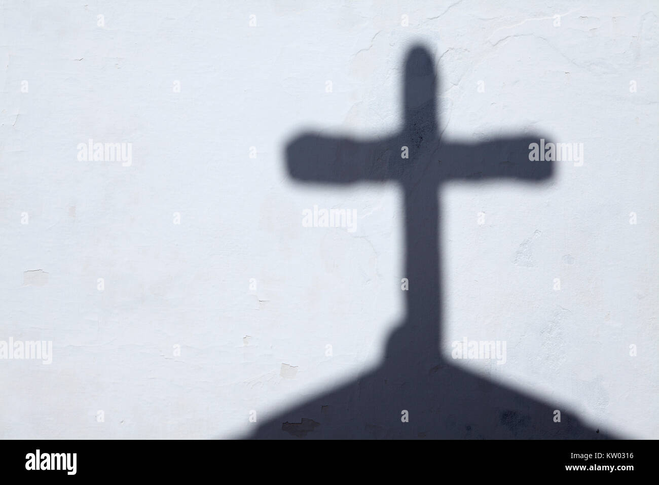 The crucifix on a chapel casts a shadow in a while wall in Marinha ...