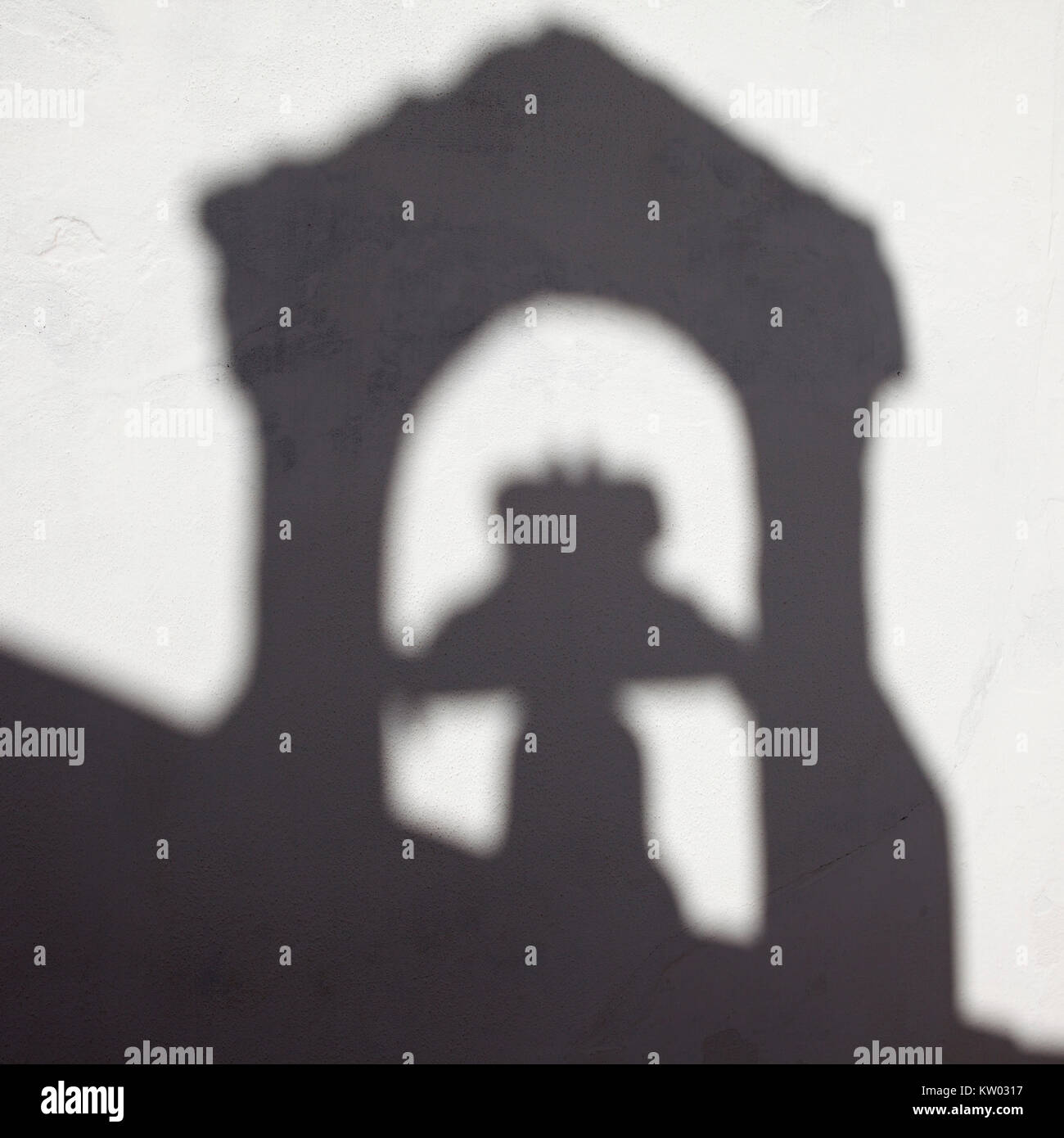 The belfry of a chapel casts a shadow in a while wall in Marinha Grande ...