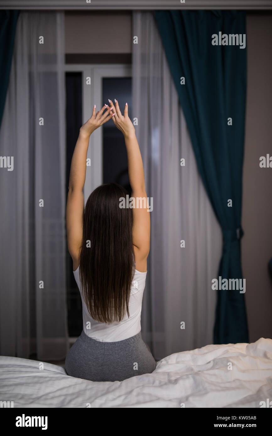 Woman wake up in the night and stretching on the bed. Night wake up for ...
