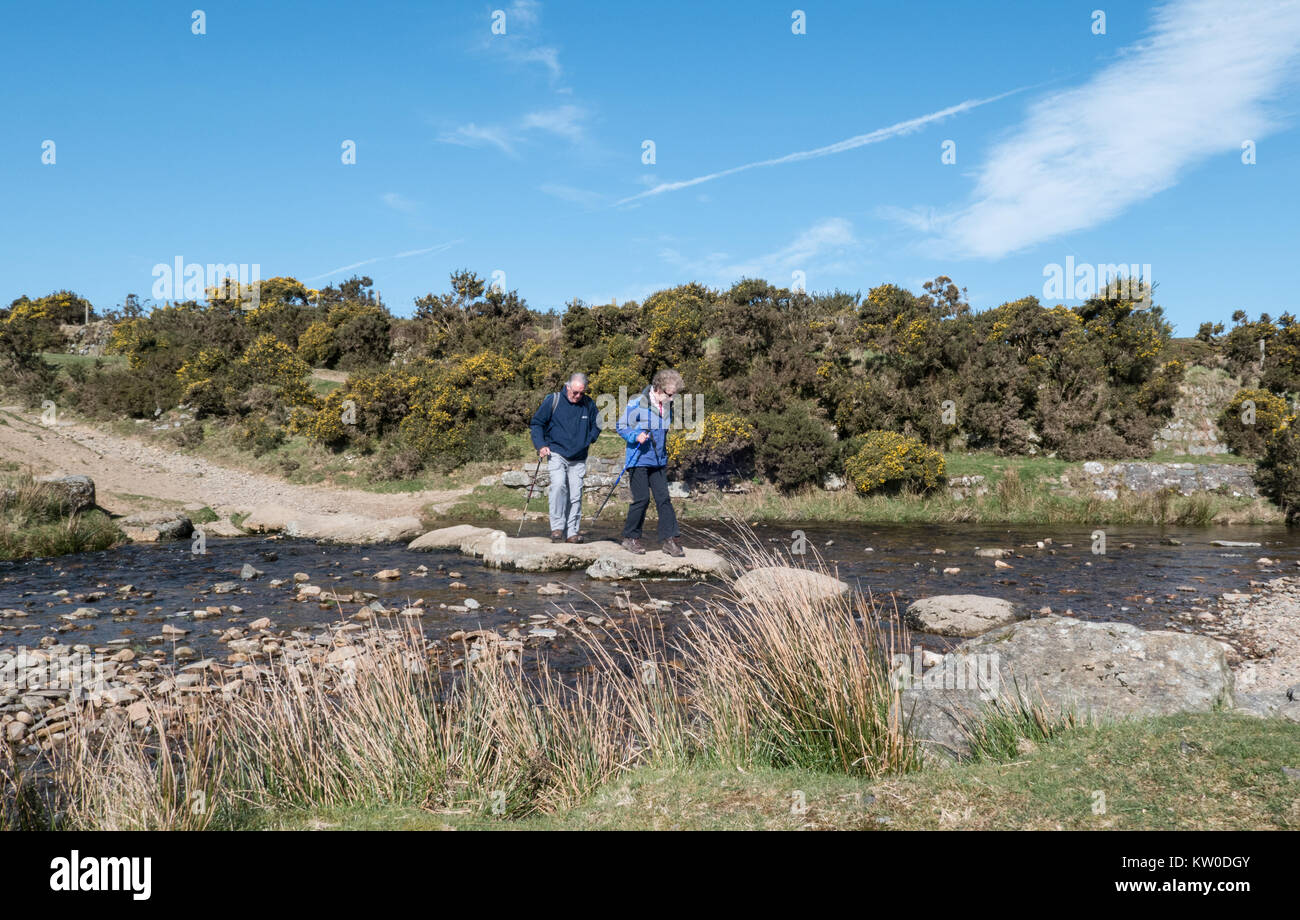 Walkers traverse a river using stepping stones near Lydford in Devon ...