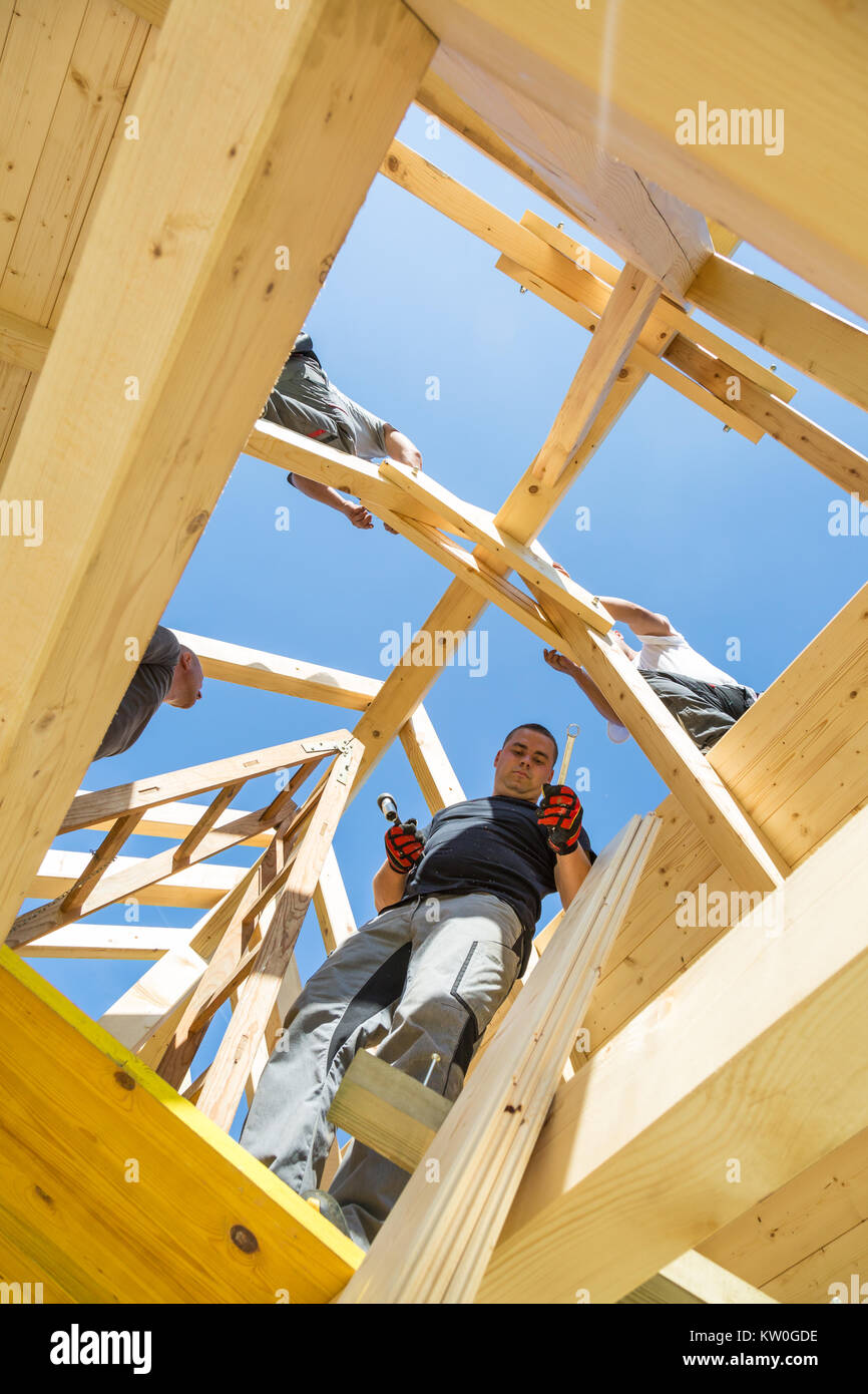 Roof builders mounting prefabricated wooden roof construction ...