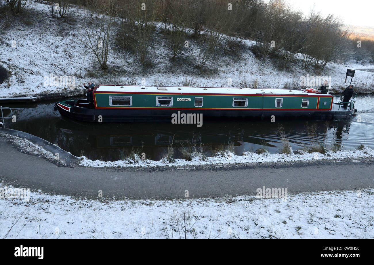 A canal boat makes it way along a frost covered Union canal near the ...