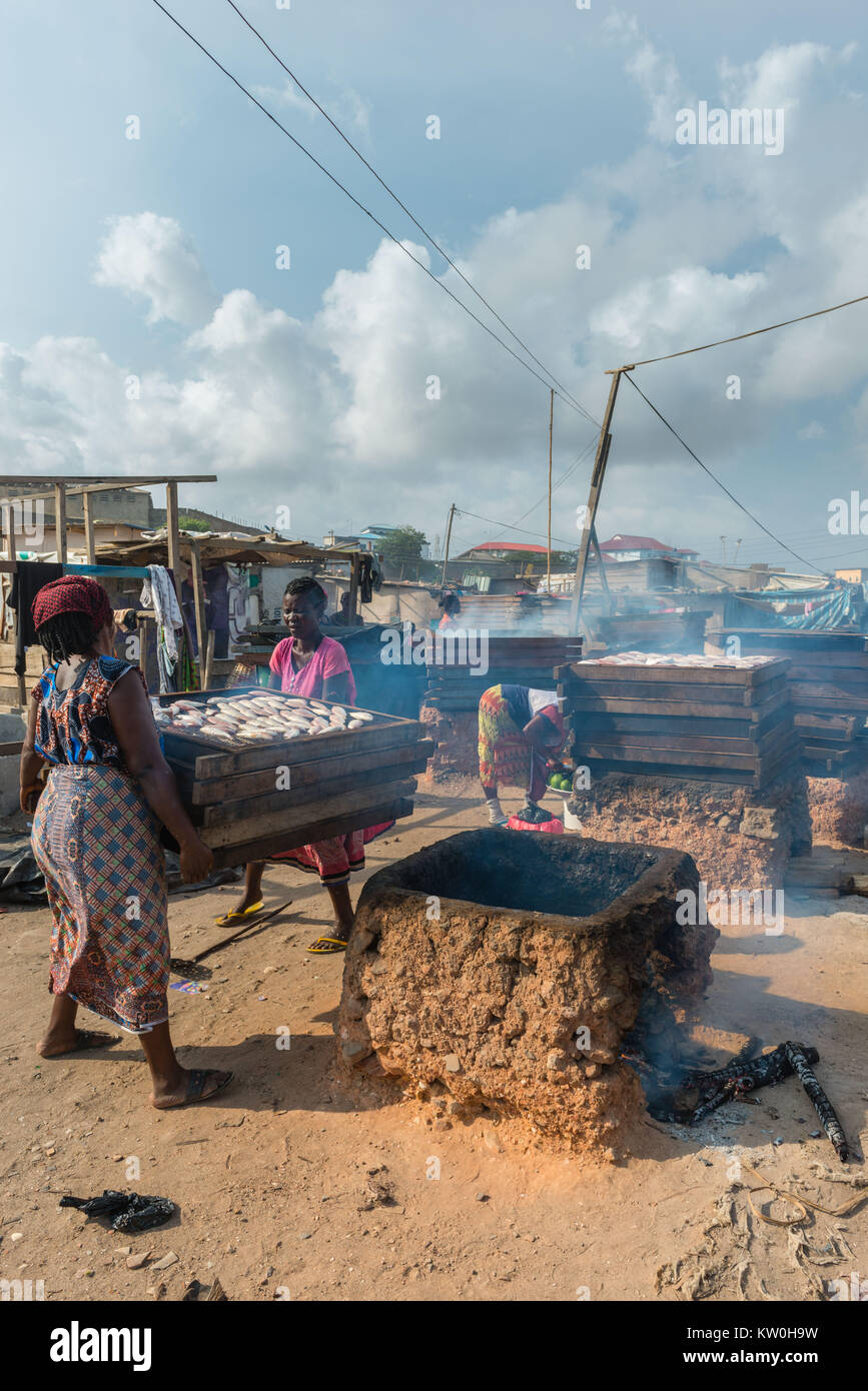 Two women smoking fish over a clay oven, Jamestown Fishing Village ...
