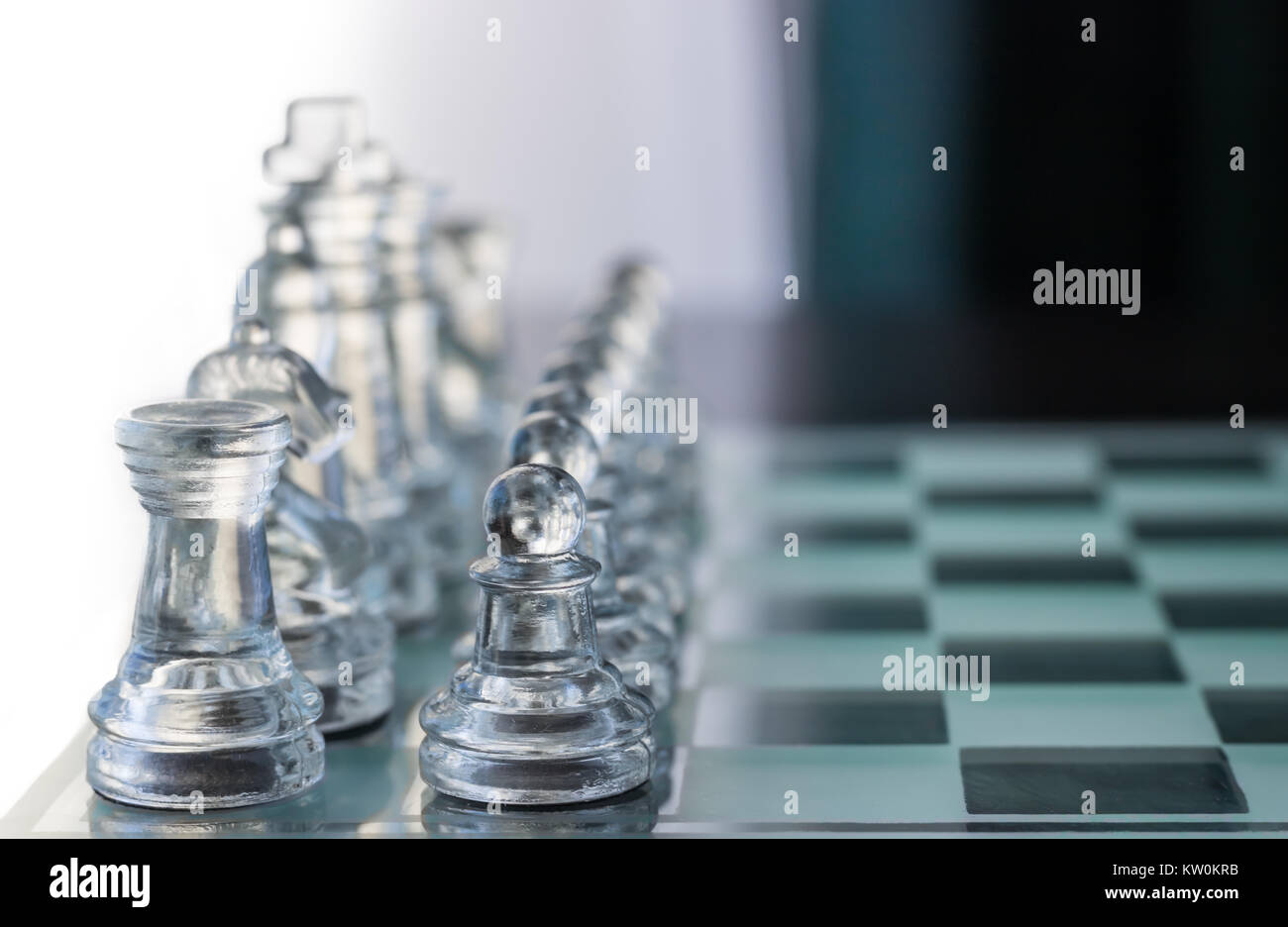 A clear glass chess set is set up and ready to play. The background is ...