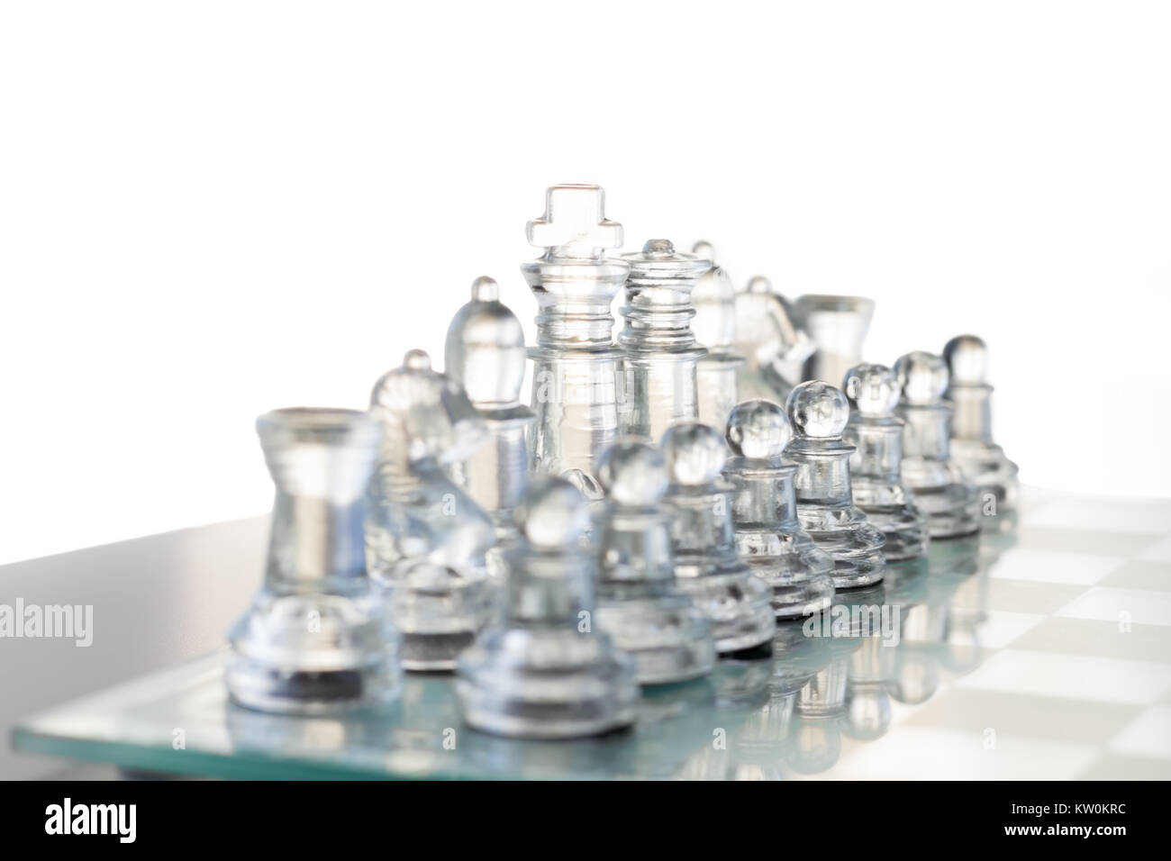 A clear glass chess set is set up and ready to play. The background is ...