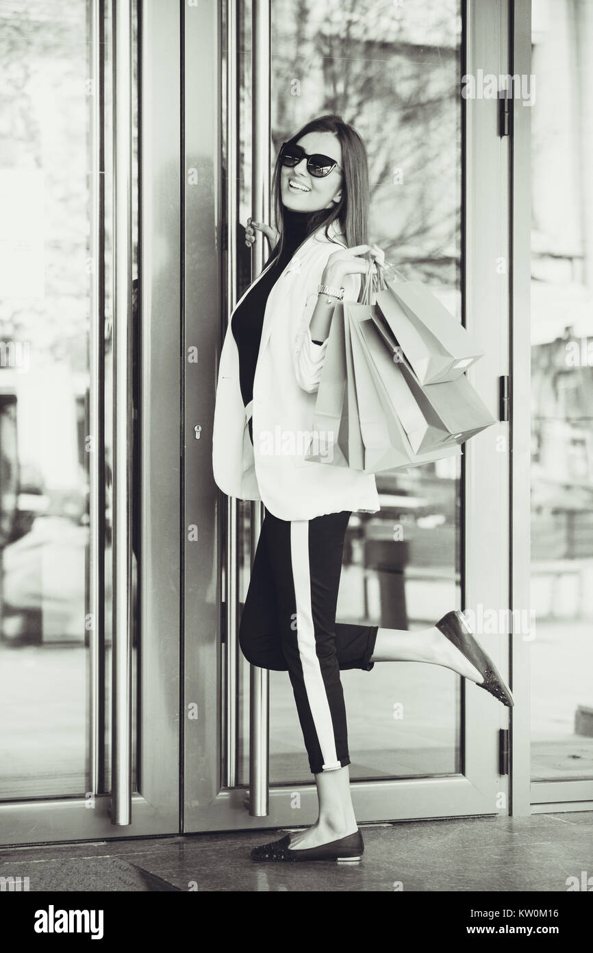 Happy young woman with shopping bags entering shop. Happy woman going ...