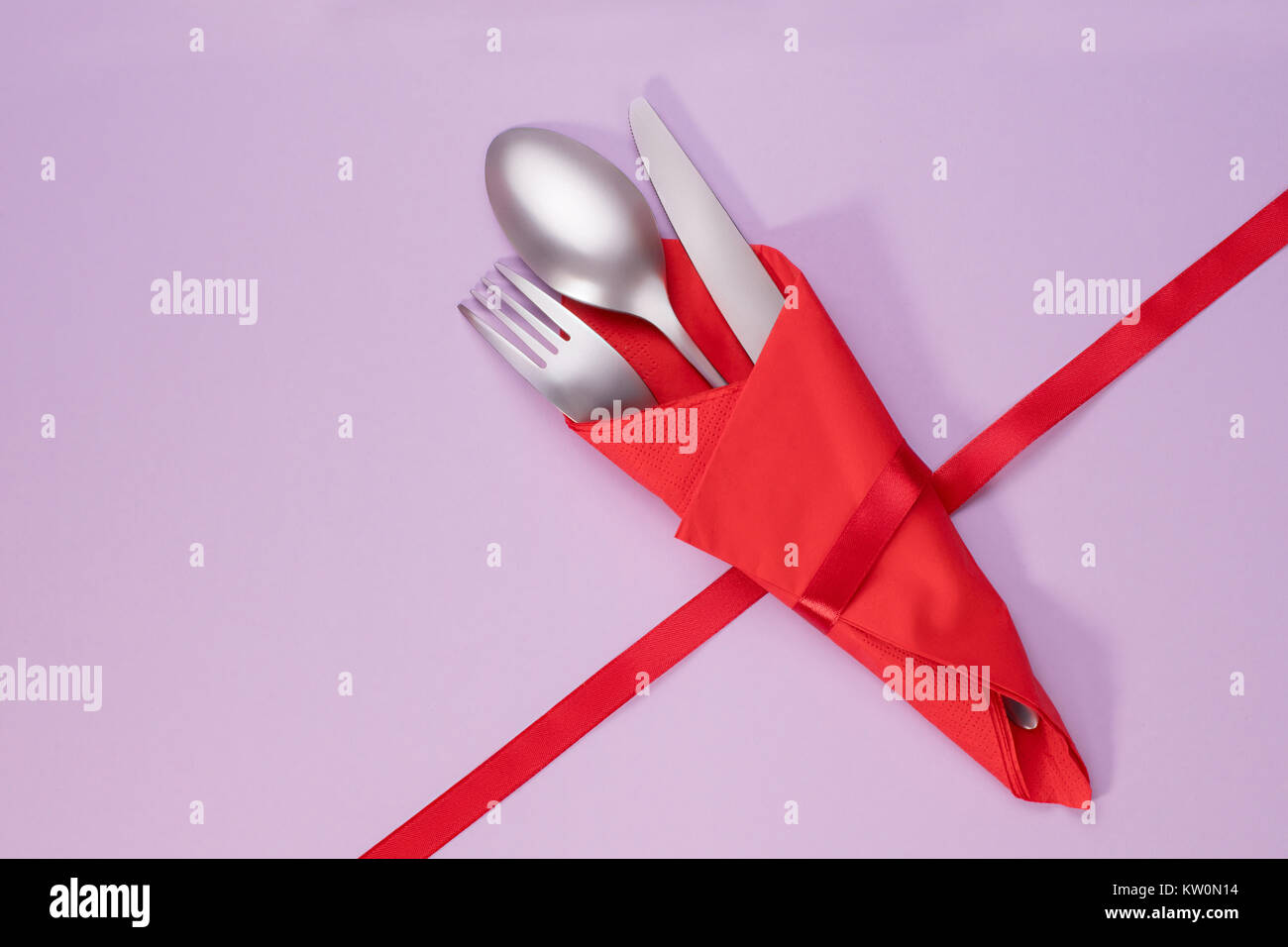Cutlery and napkin with red ribbon. On violet background. Table setting ...