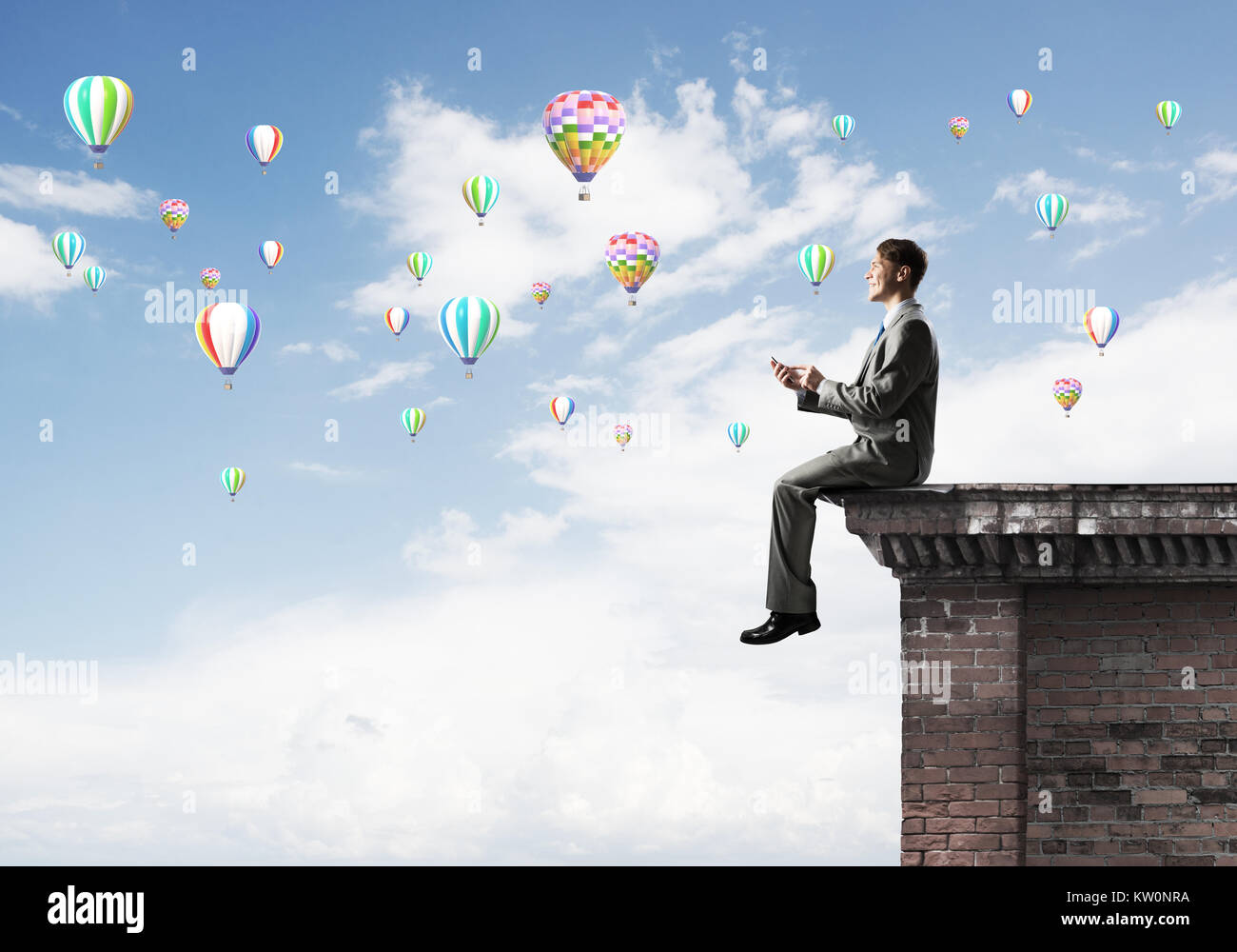 Man on roof edge usinng smartphone and aerostats flying in air Stock ...
