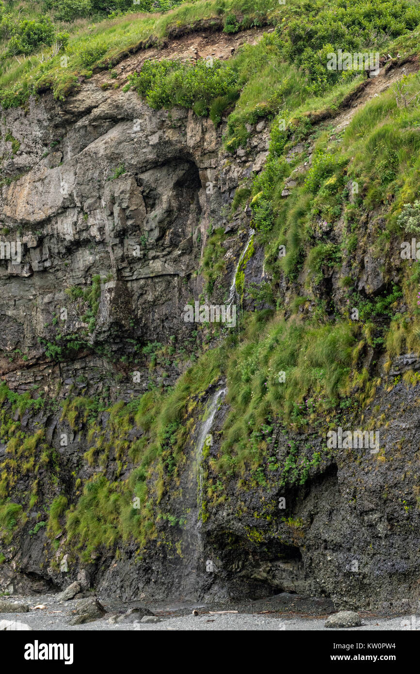 A small waterfall cascades down the rock cliffs along the Cook Inlet at ...
