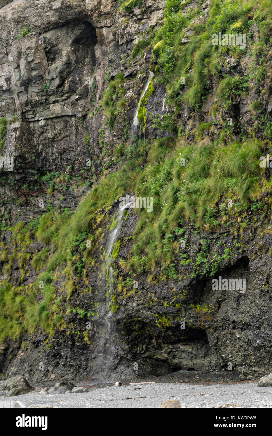 A small waterfall cascades down the rock cliffs along the Cook Inlet at ...