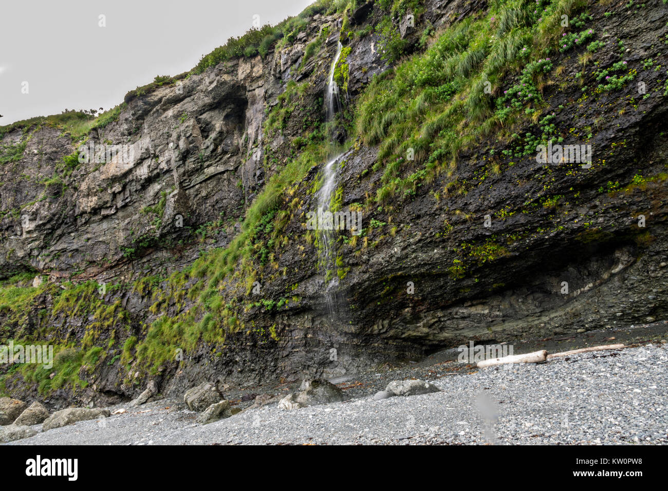 A small waterfall cascades down the rock cliffs along the Cook Inlet at ...