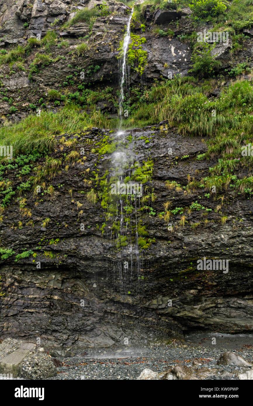 A small waterfall cascades down the rock cliffs along the Cook Inlet at ...