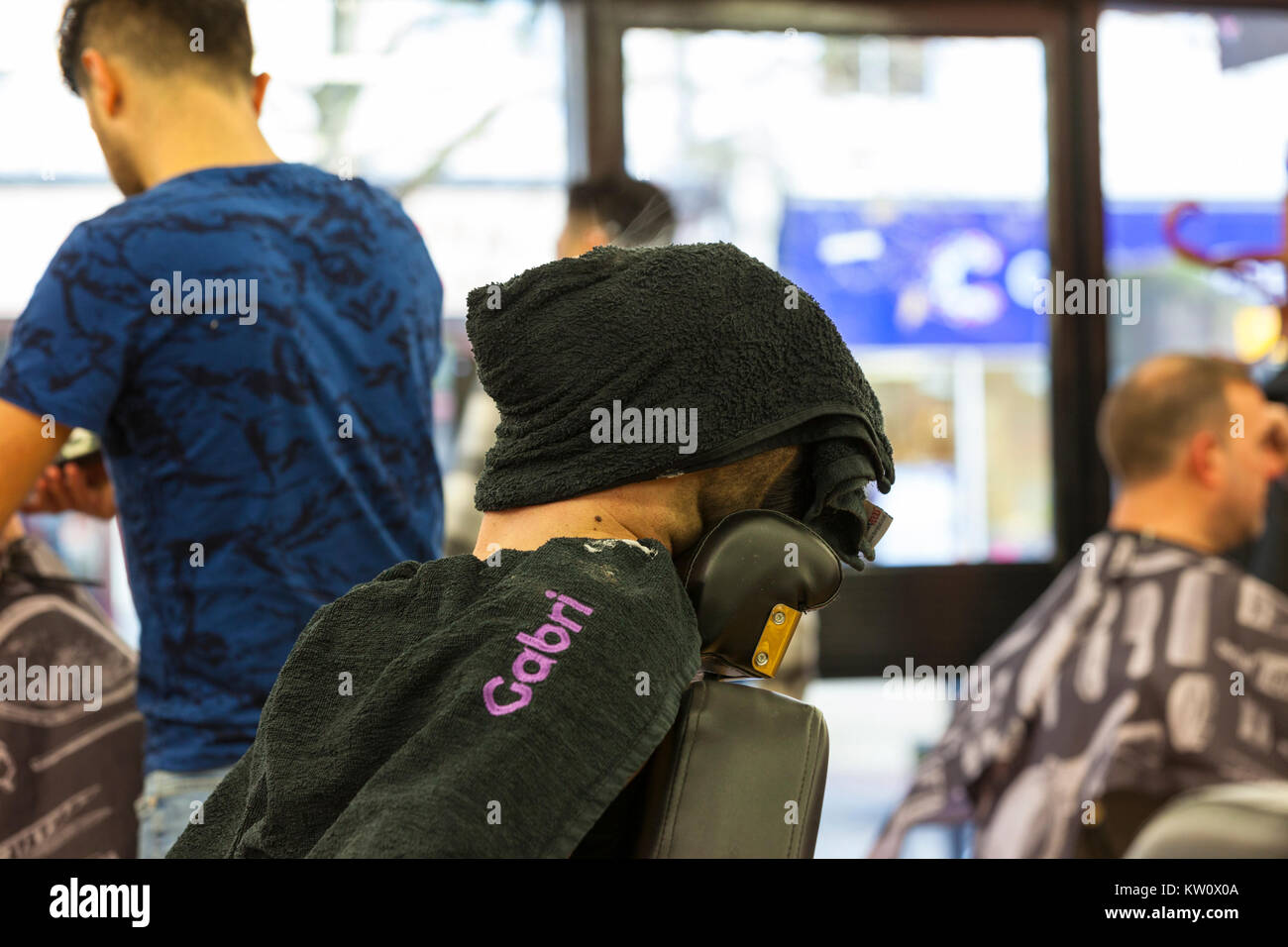 A man has a towel wrapped around his face, steam clean, barbers ashford kent Stock Photo - Alamy