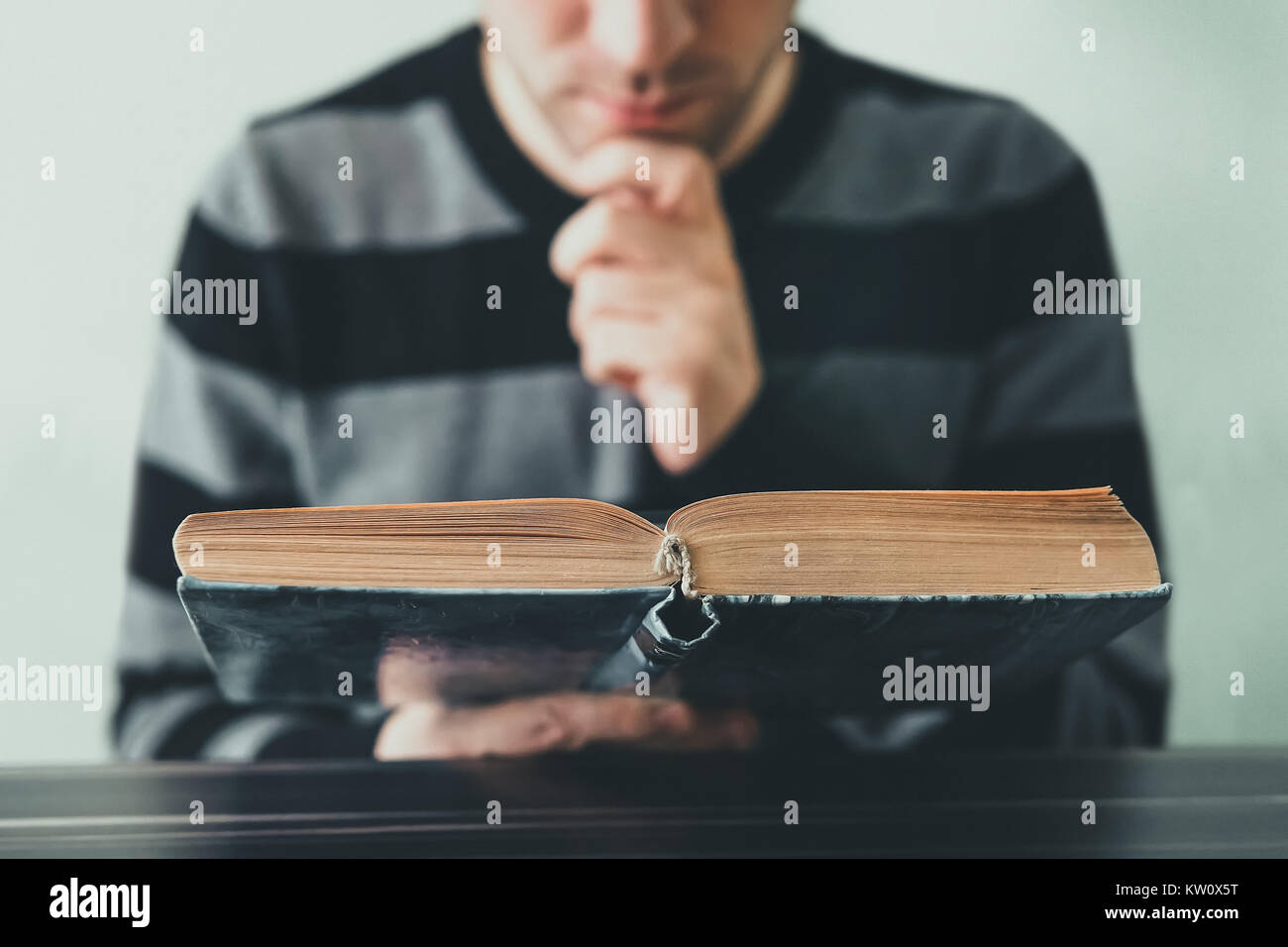 Young man opening and reading a book, close up. Young adult carefully ...