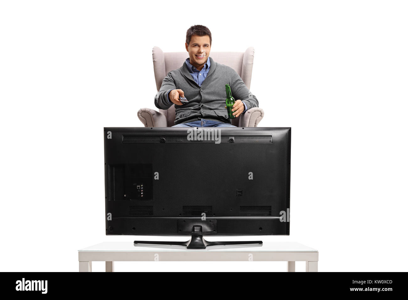 Young guy with a remote control and a bottle of beer sitting in an ...