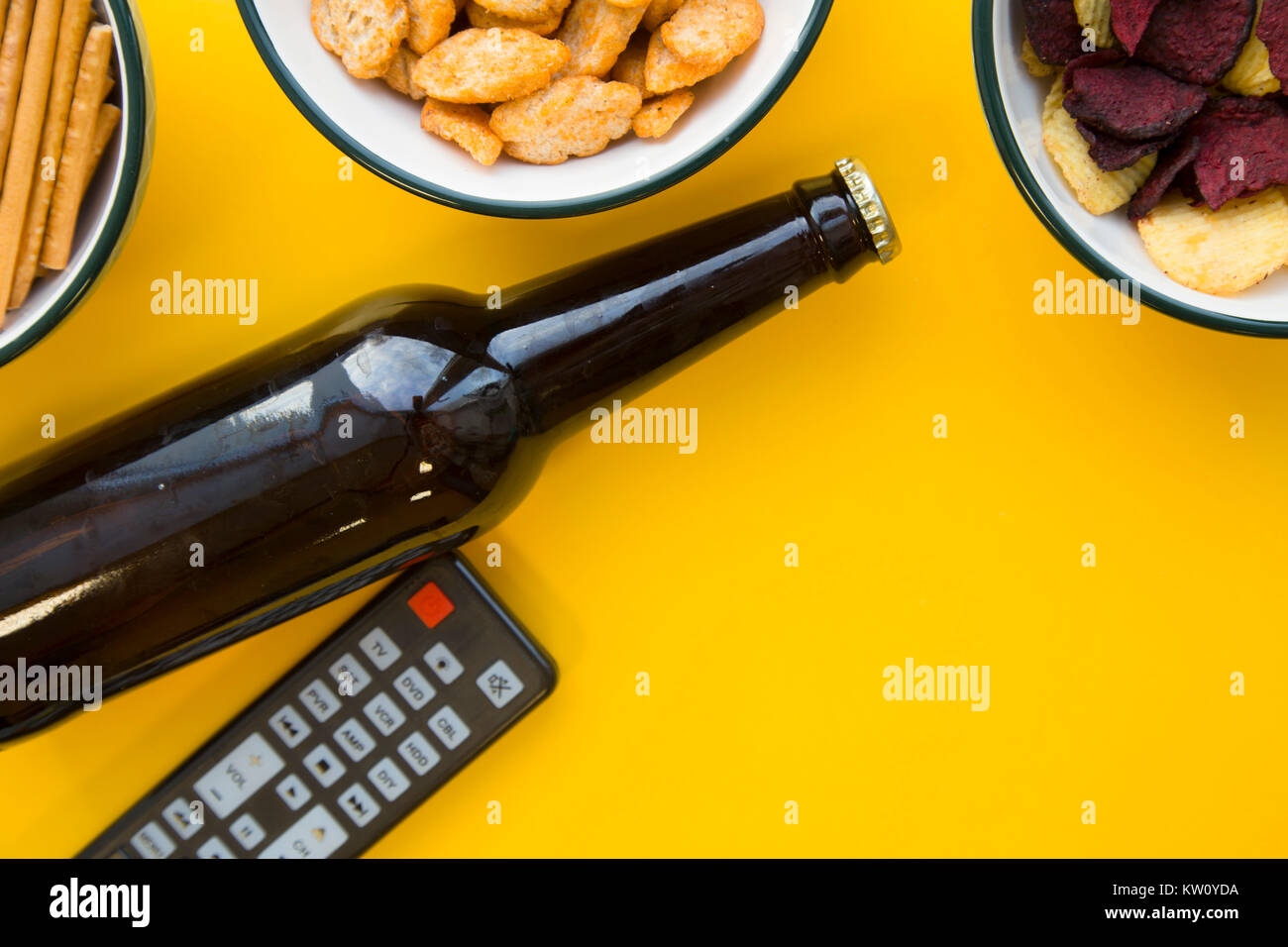 Watching sport channel with friends. Crunchy snacks in bowls, a bottle ...