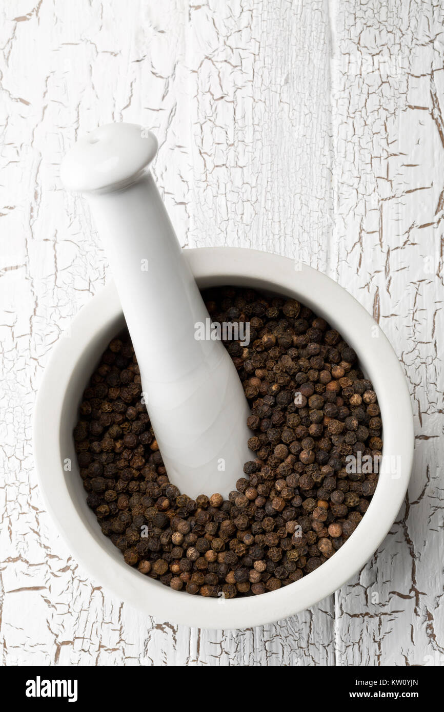 Raw, natural, unprocessed black pepper peppercorns in mortar on rustic ...