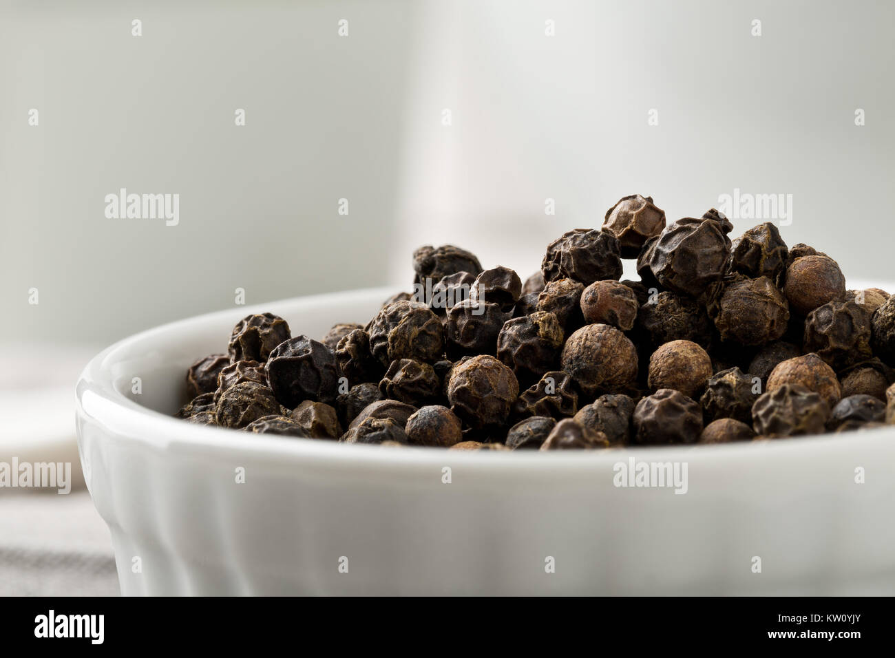 Raw, natural, unprocessed black pepper peppercorns white bowl on ...