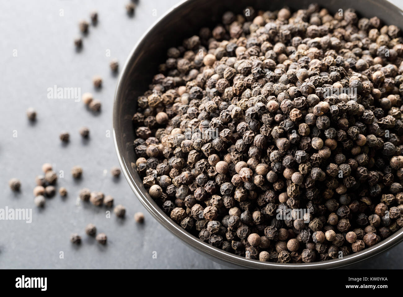 Raw, natural, unprocessed black pepper peppercorns in black bowl on ...