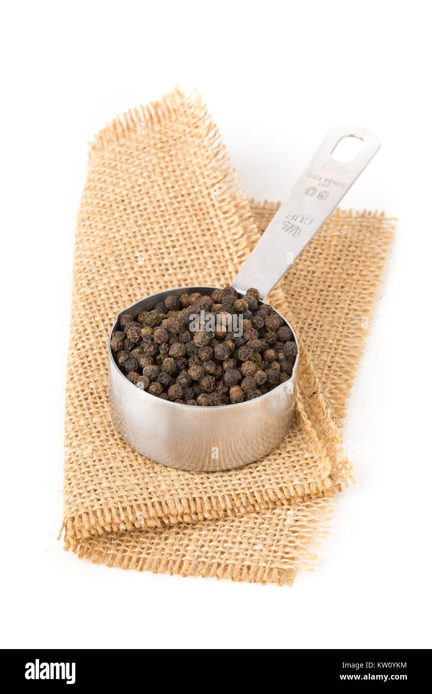 Raw, natural, unprocessed black pepper peppercorns in measuring cup on ...