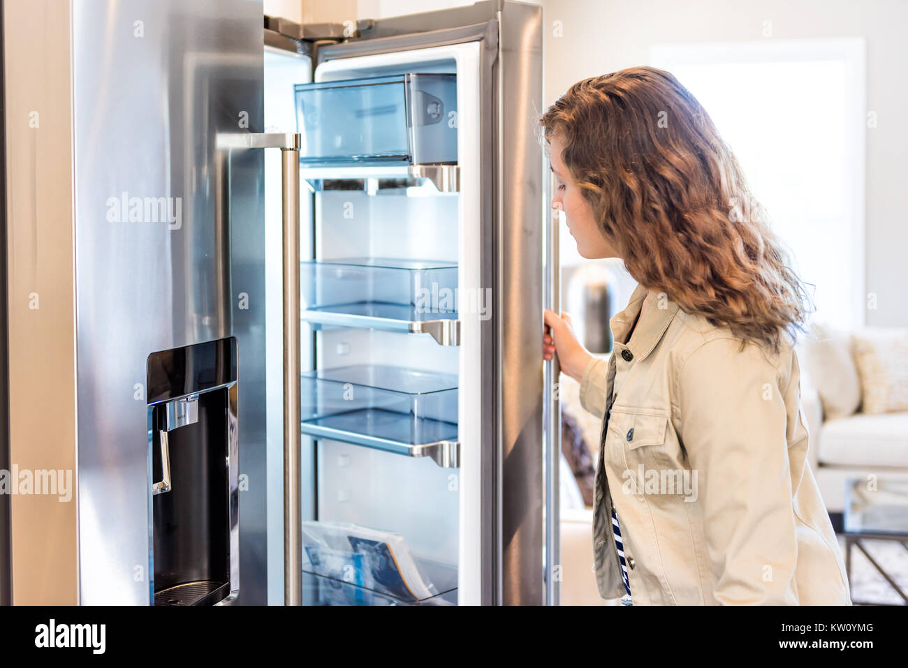 One young woman opening empty modern stainless steel chrome kitchen ...
