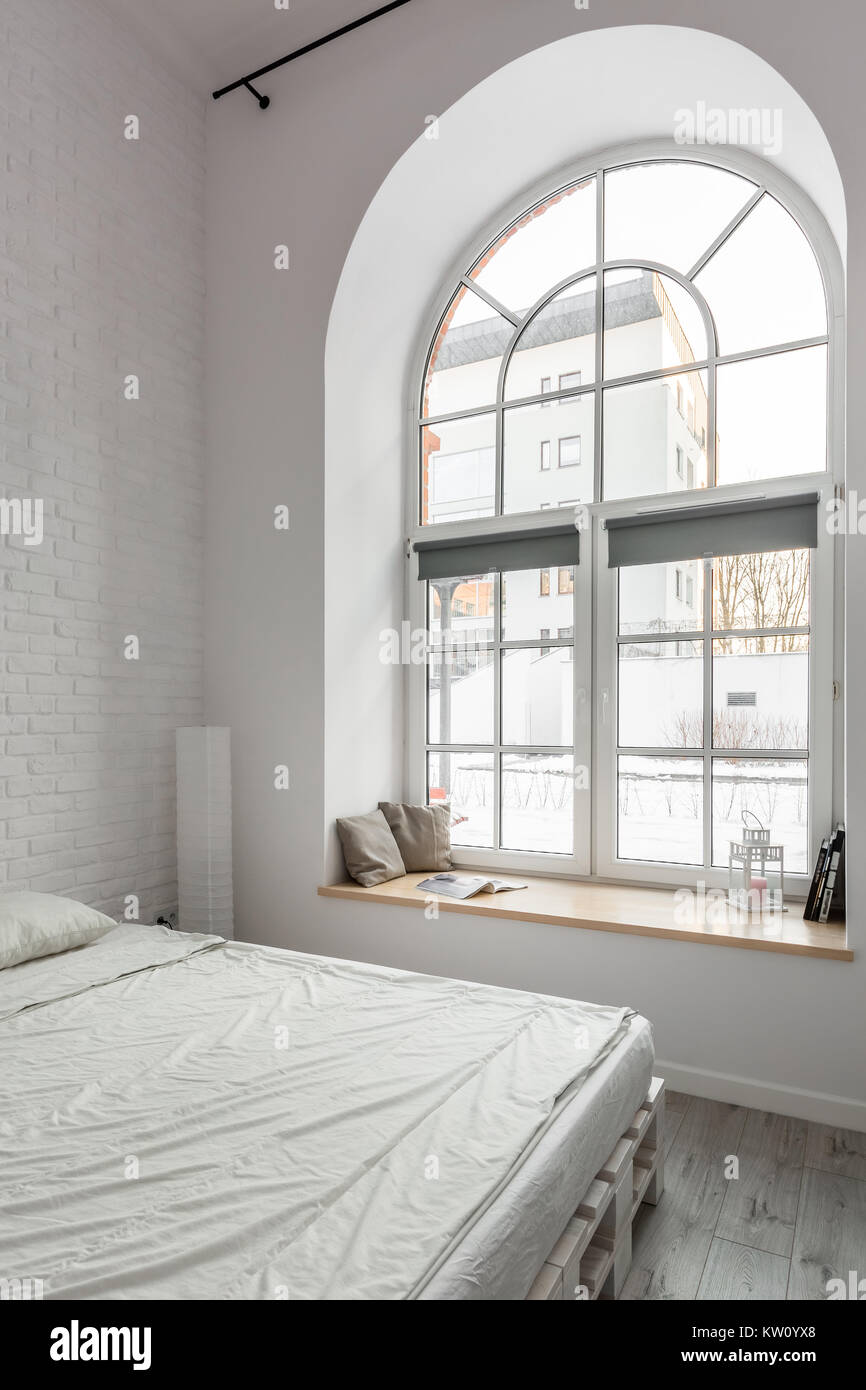 Big window with arch and glazing bars in white loft bedroom Stock Photo ...
