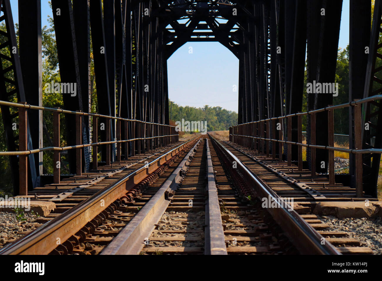 Empty train tracks on a bridge taken from a low angle, blue sky, forest ...