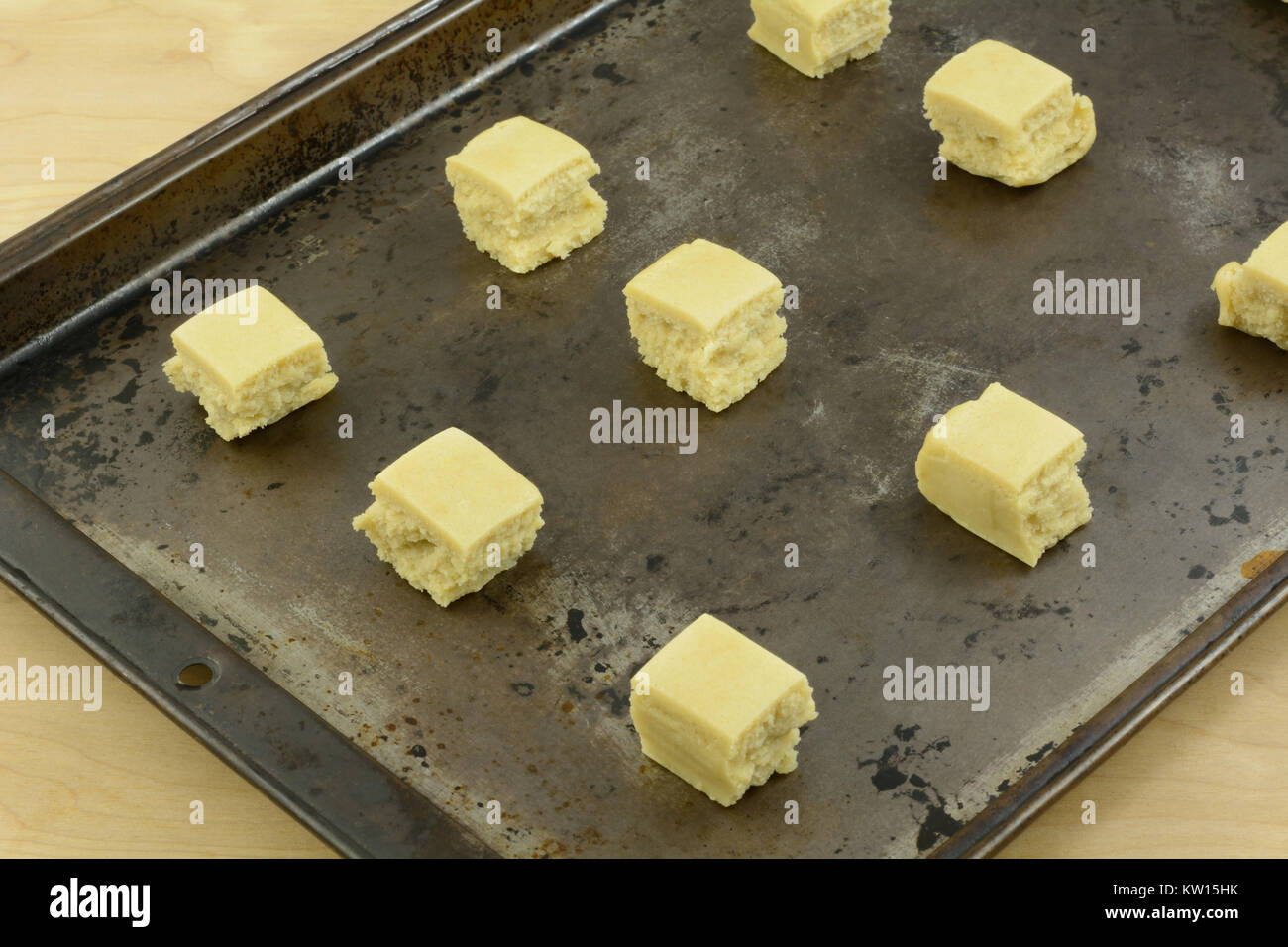 Pre-cut sugar cookie dough cubes arranged on baking pan in preparation ...