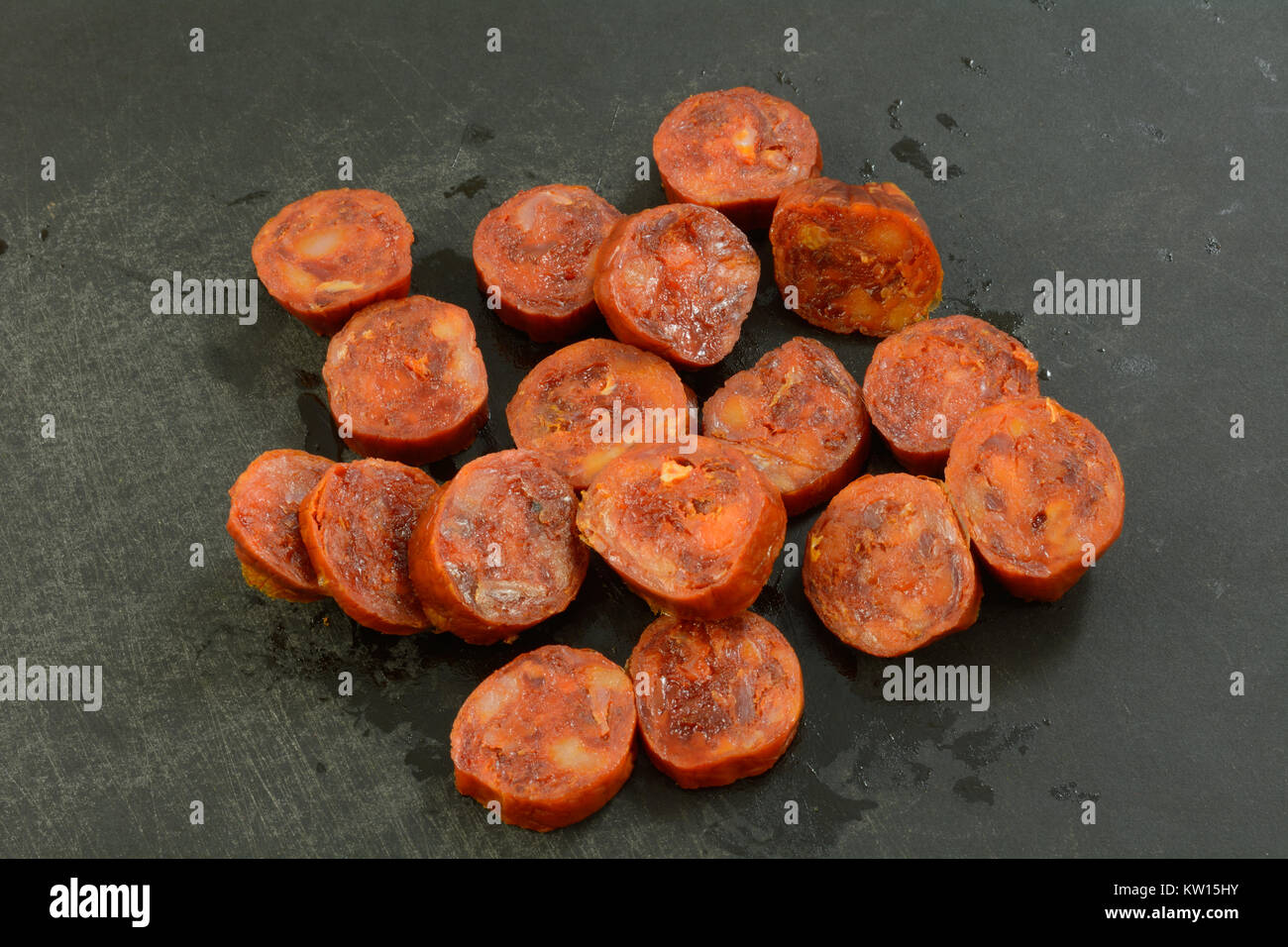 Sliced dried cured chorizo pork sausage on black cutting board as ...