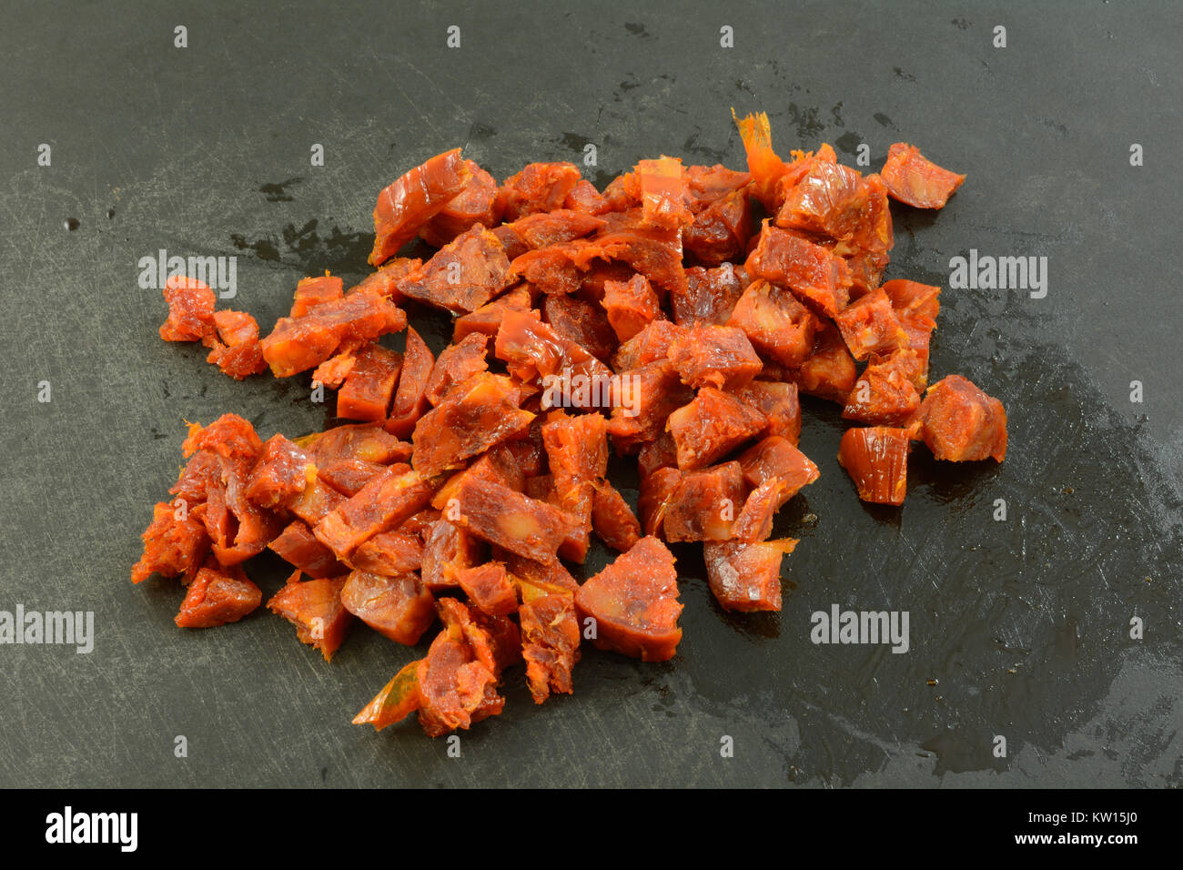 Chopped dried cured chorizo pork sausage on black cutting board in ...