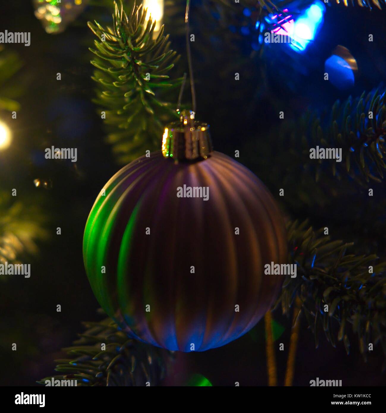Round Christmas tree decoration hanging from branch - illuminated from ...