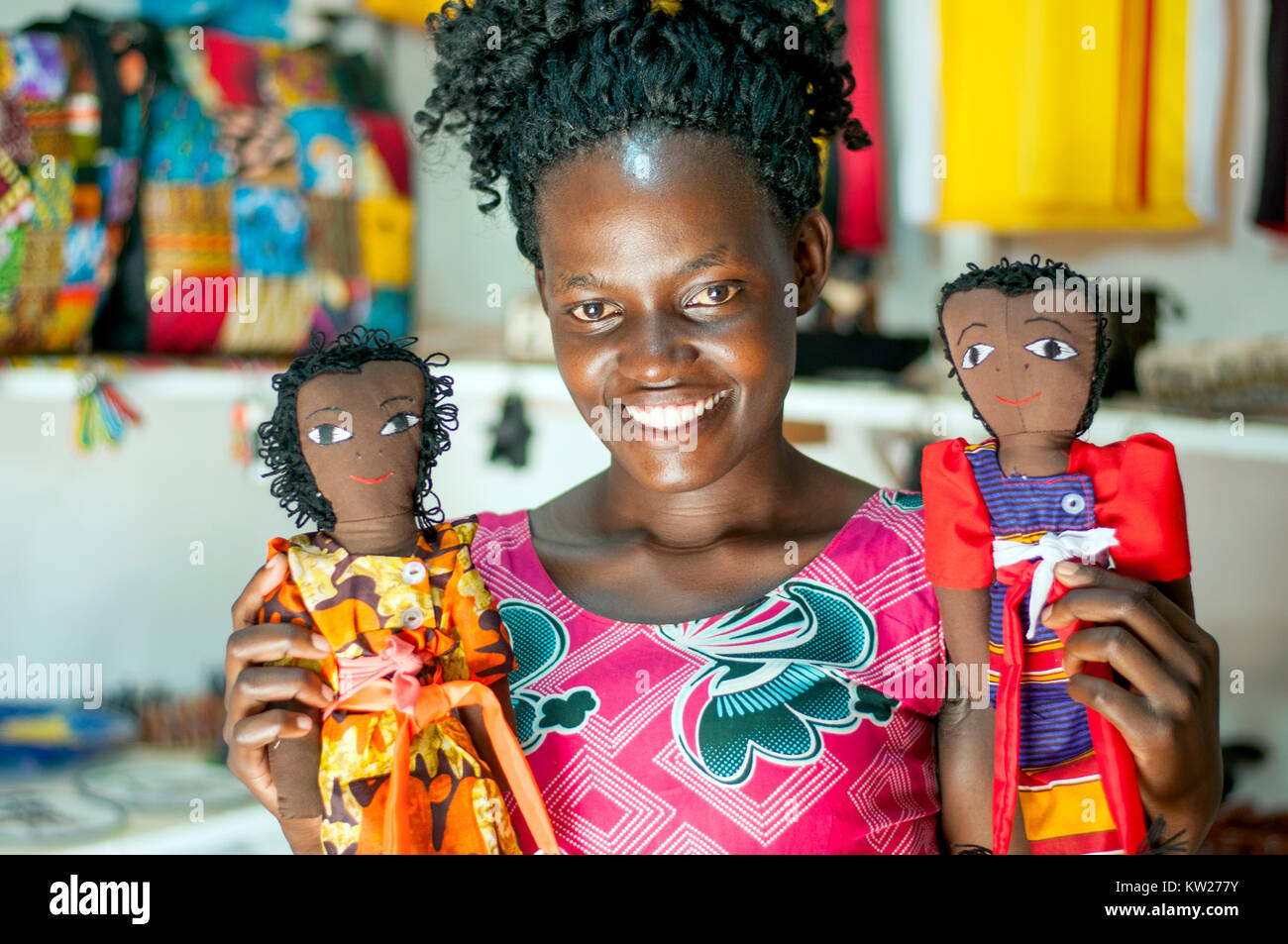 Craft stall proprietor holding tribal dolls, Handicraft Centre, Entebbe ...