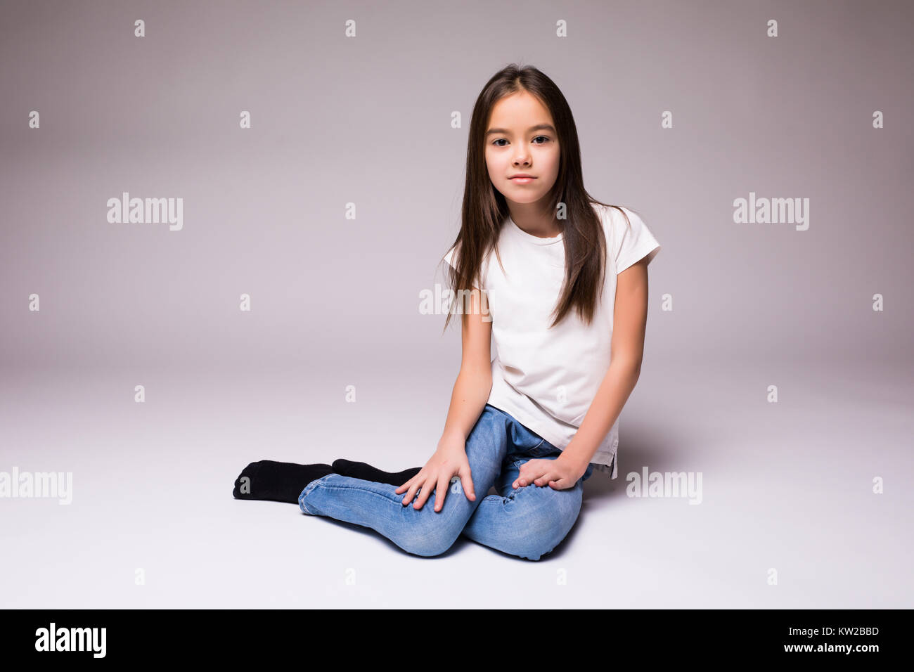 Lovely Little Girl Sitting On The Floor Isolated On White Background