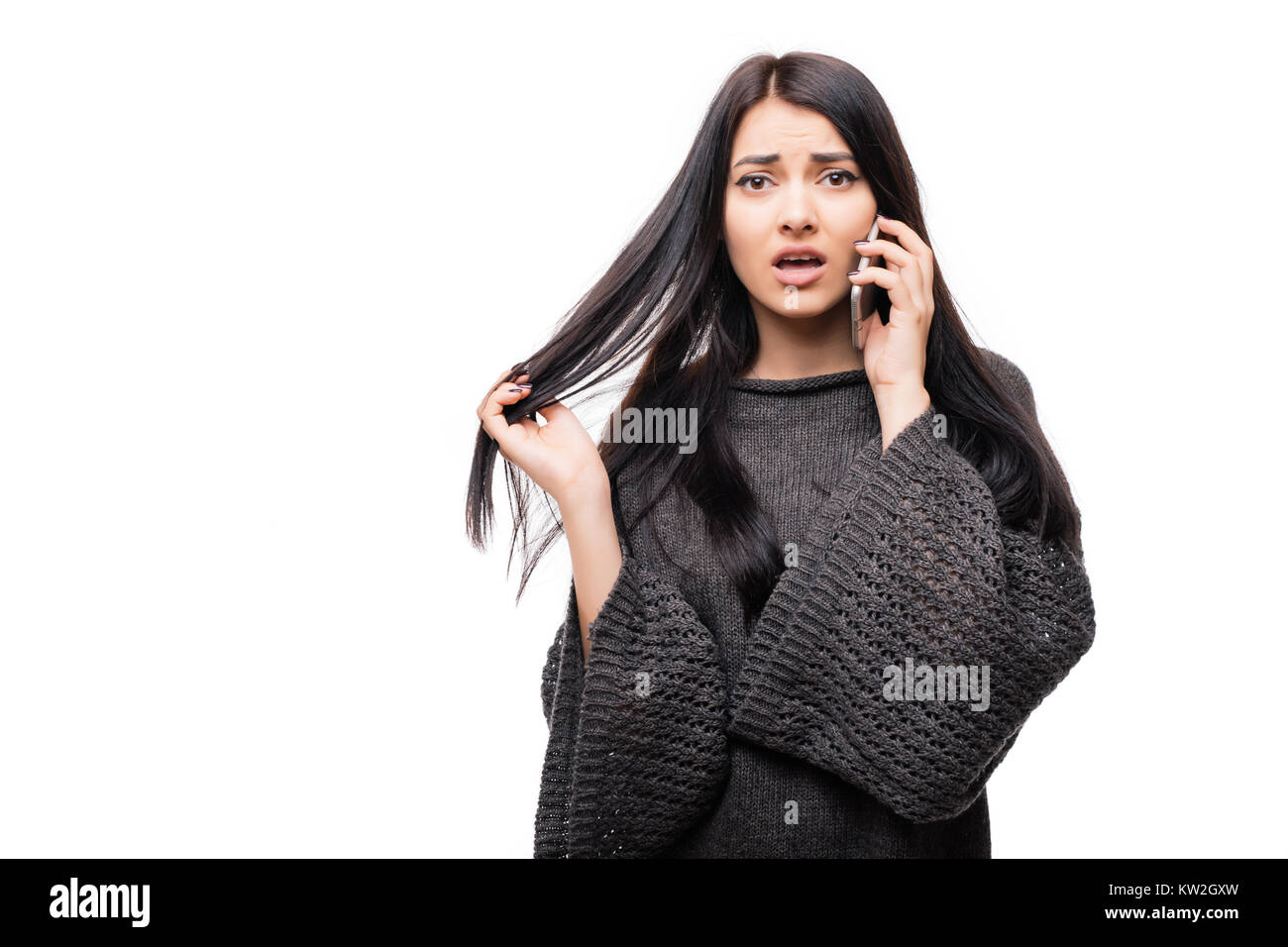 Portrait of young sad girl talking on her phone over white background ...