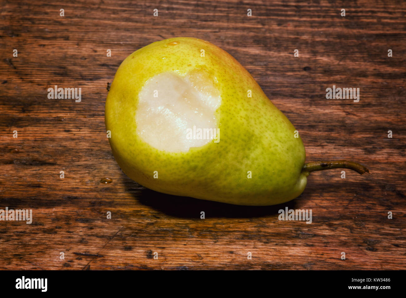 close up of pear with bite mark on rustic wooden table Stock Photo - Alamy