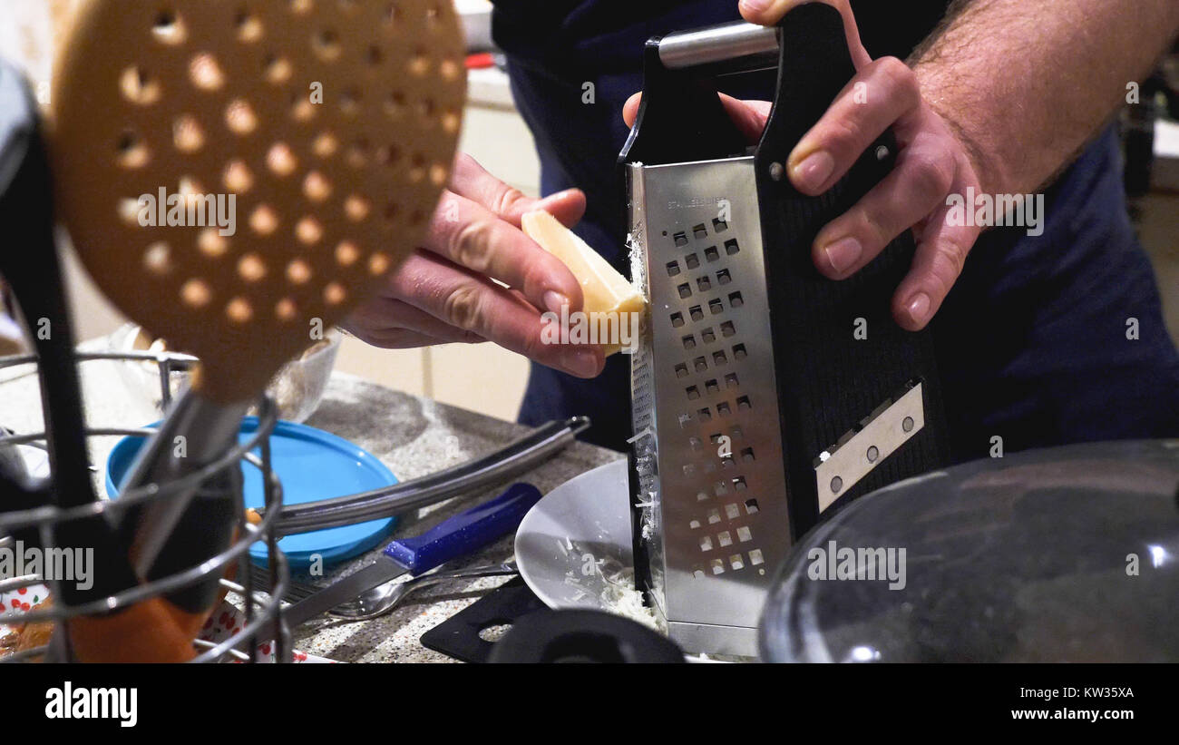 Male hands grating cheese on busy kitchen table - cooking, food and ...