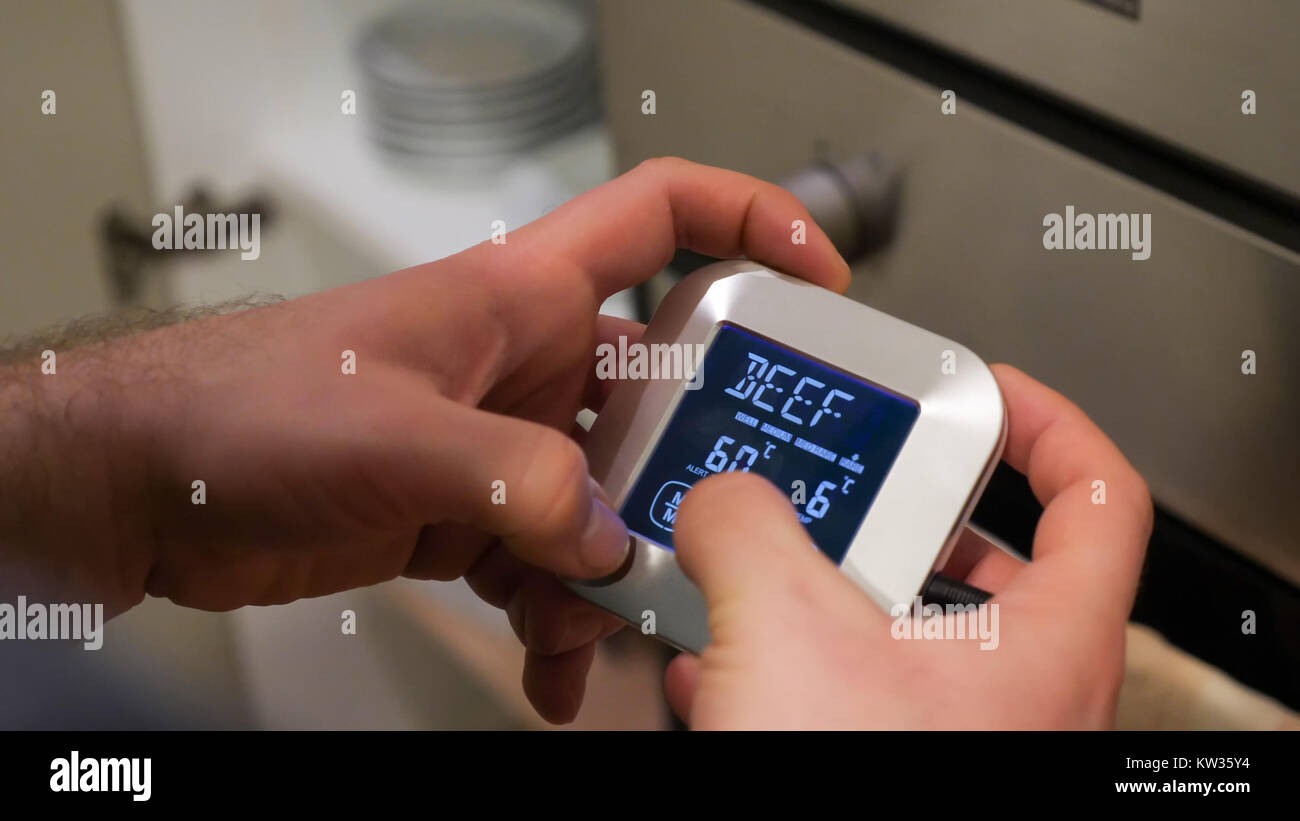 Male hands set up temperature control unit for roasting beef meat in ...