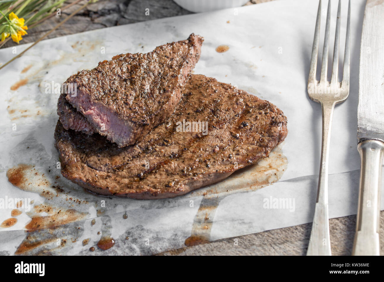 Beef steak on a rustic wooden log, with garlic sauce and old cutlery ...