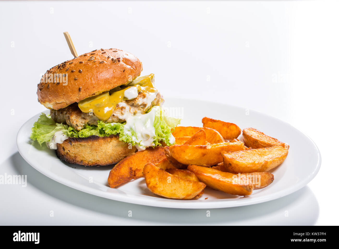 Tasty chicken burger with wedges, on a white plate Stock Photo - Alamy