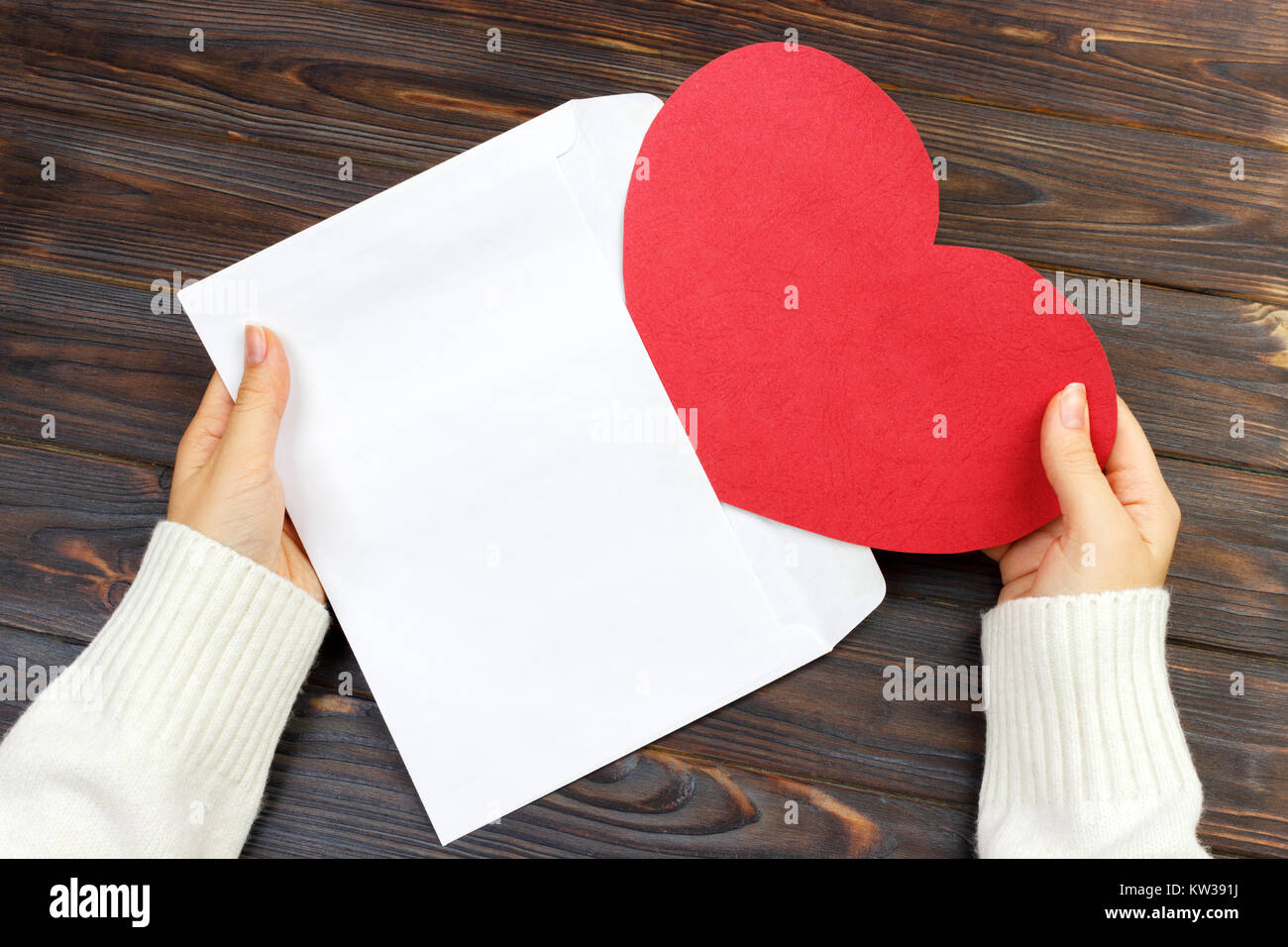 A female woman hand hold open a envelope and post card on the wood desk ...