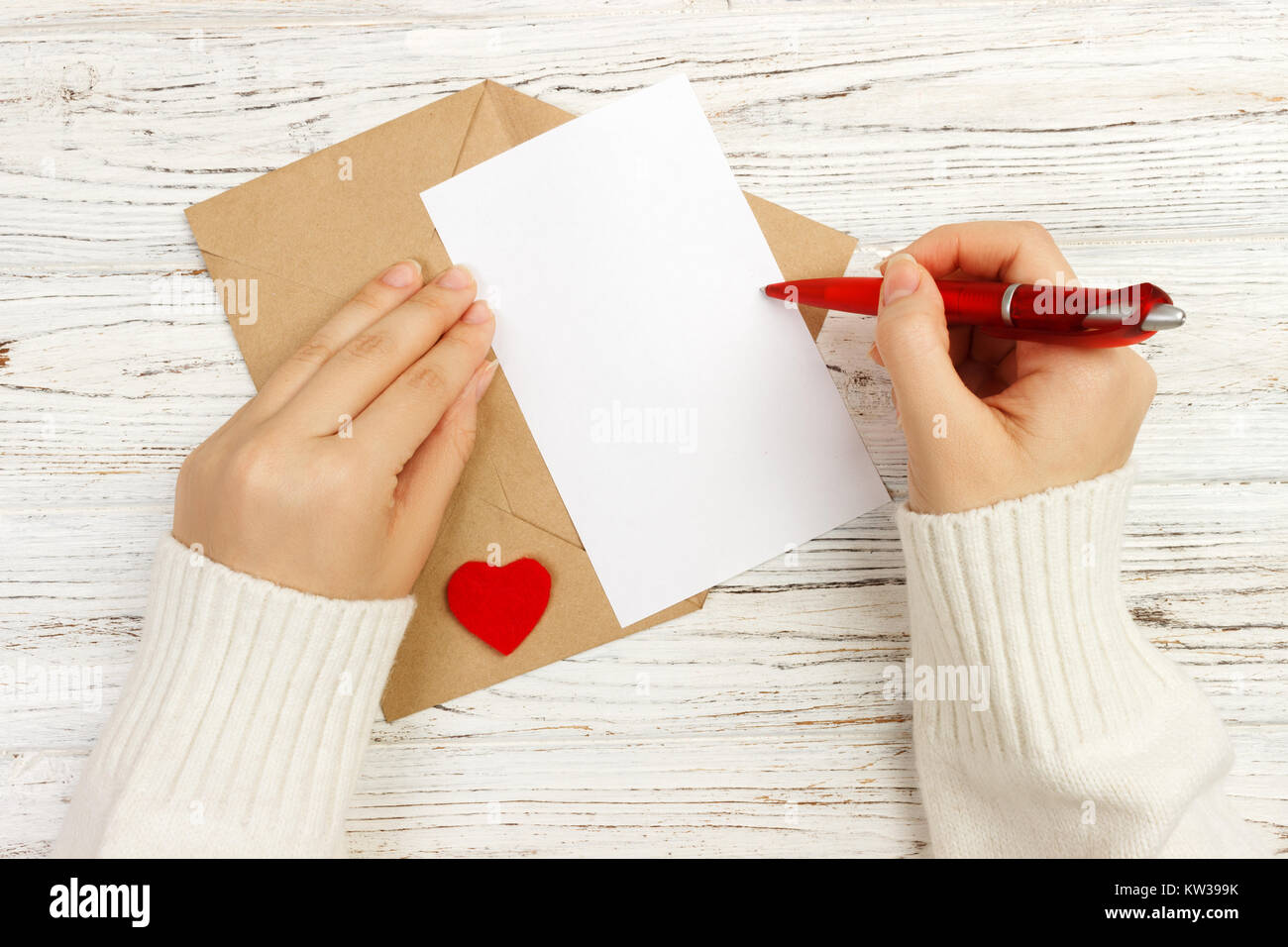 Hand of girl writing love letter on Valentine Day. Handmade postcard ...