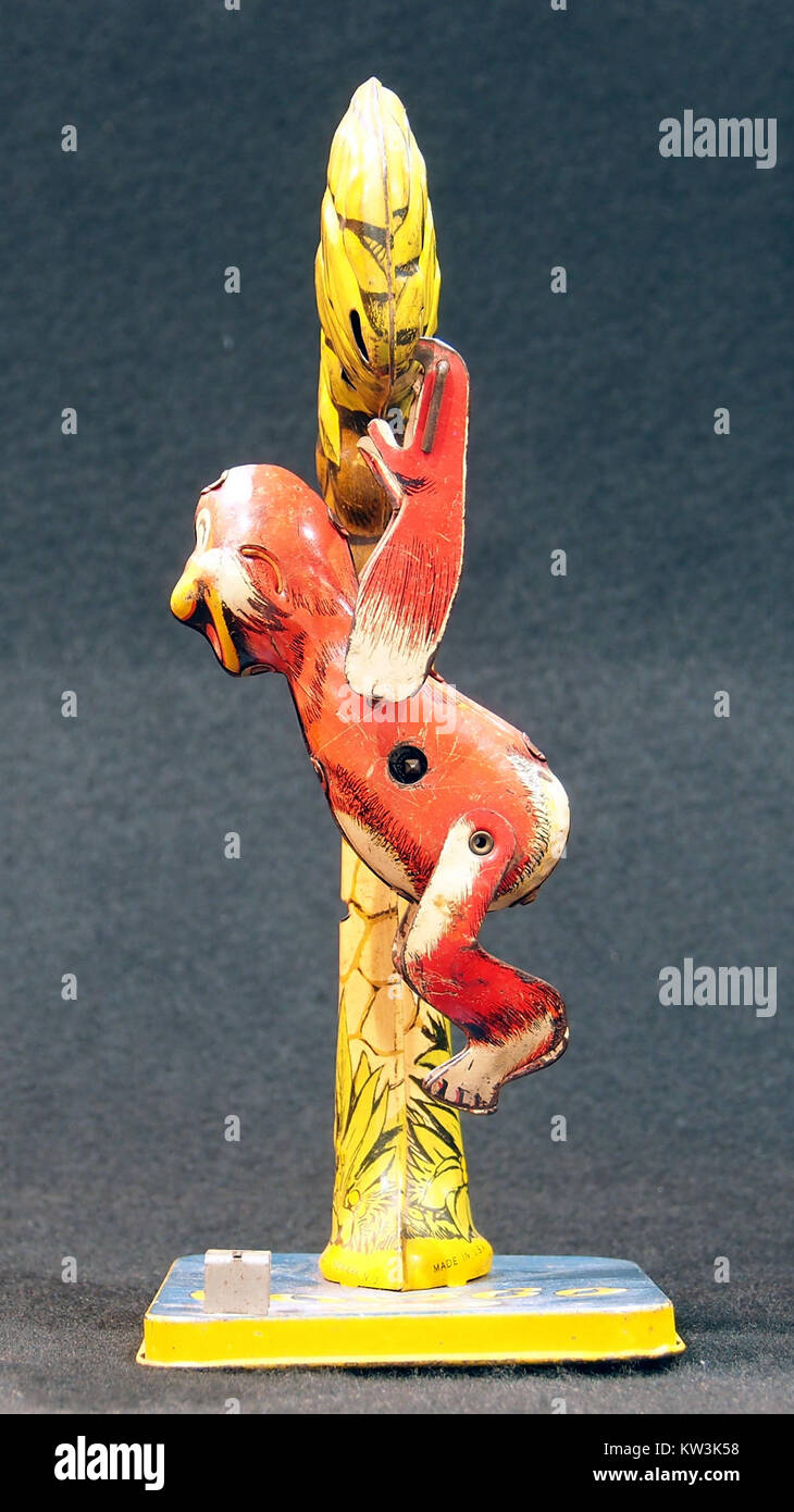 The image depicts a tin toy monkey positioned in a tree, showcasing mid ...