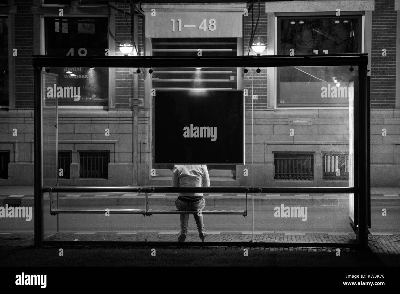 This black-and-white photograph captures a woman at night, emphasizing ...