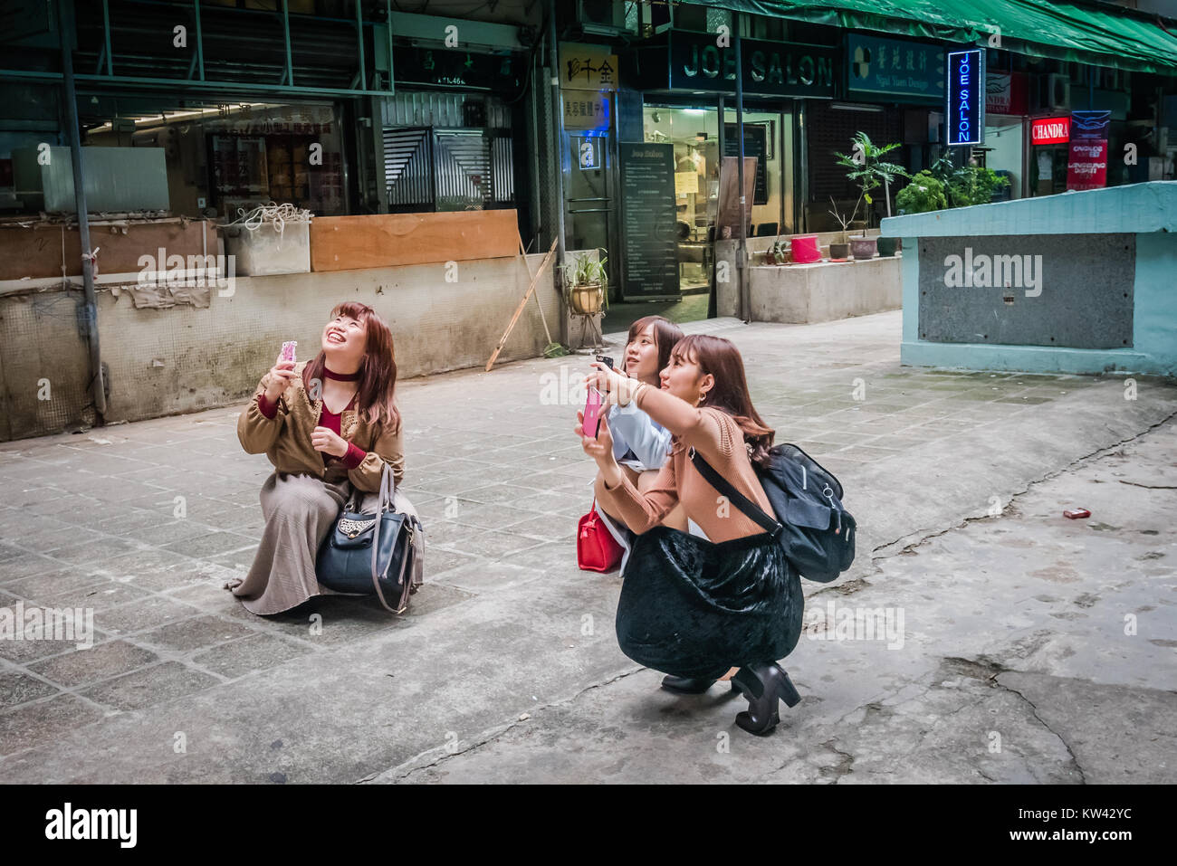 three asian women crouching on the ground Stock Photo - Alamy